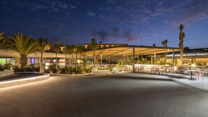 Resort com área de estar ao ar livre, palmeiras e área coberta.