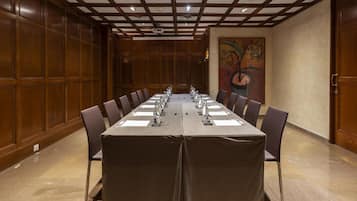 Uma sala de conferência com uma mesa comprida, cadeiras e uma tela de projeção.