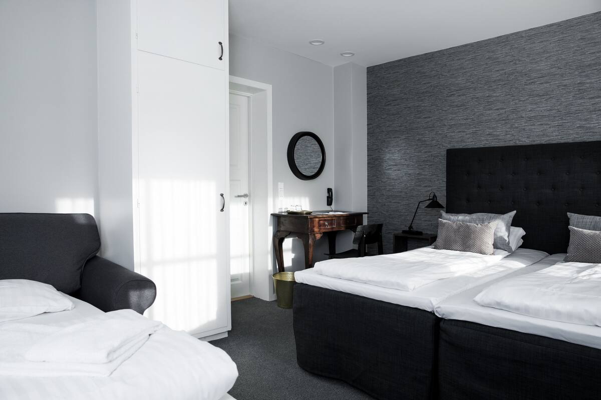 Quarto de hotel moderno com uma cama grande, uma escrivaninha e uma cadeira.