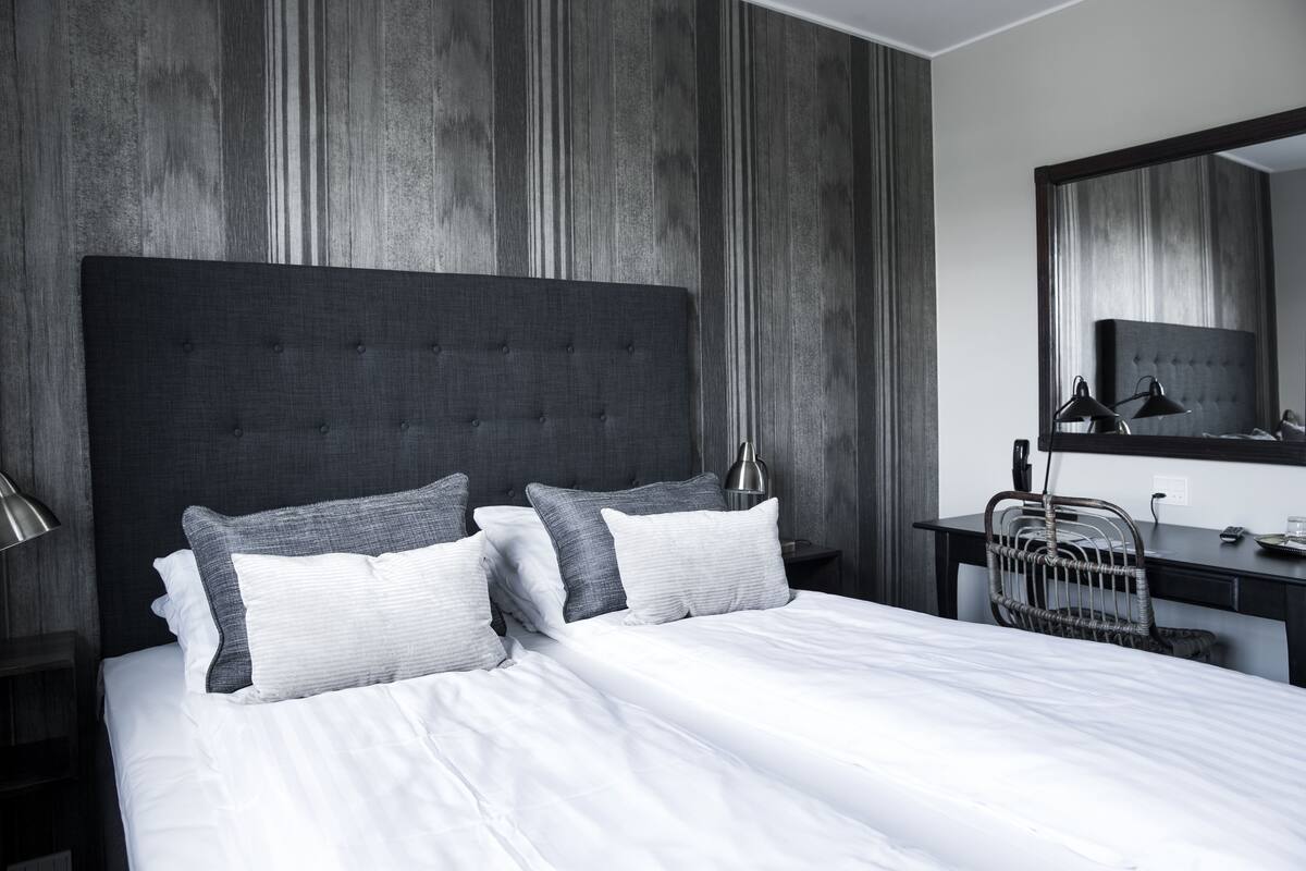 Quarto de hotel moderno com uma cama grande, uma escrivaninha e uma cadeira.