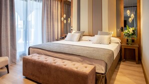 Quarto moderno com uma cama grande, um banco e uma mesa de cabeceira com um vaso de flores.