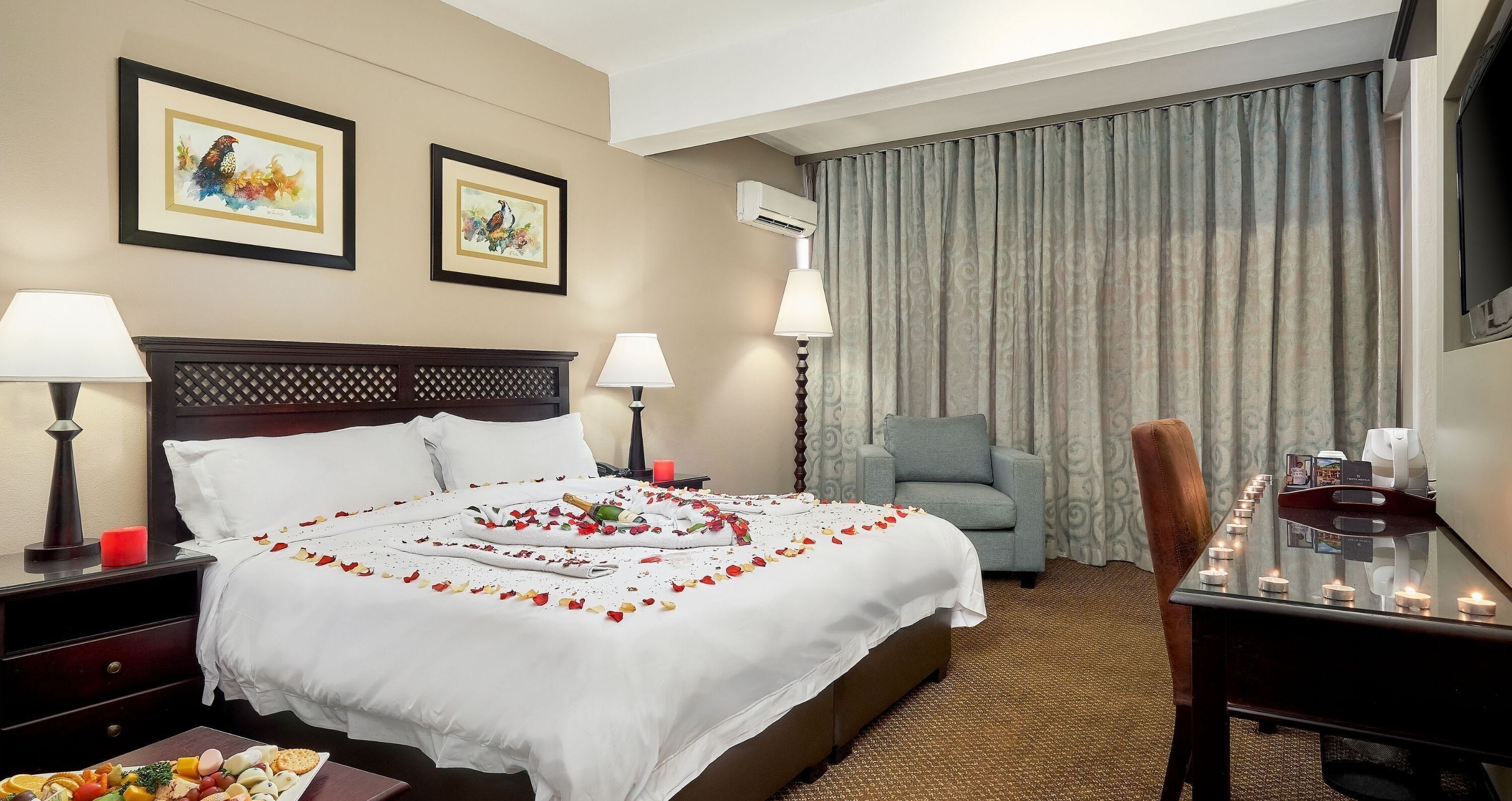 Quarto de hotel com cama bem arrumada, duas obras de arte emolduradas na parede, uma escrivaninha com um laptop e uma cadeira.
