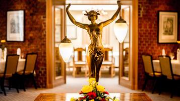 Uma estátua de mulher segurando balanças, colocada sobre uma mesa com flores.