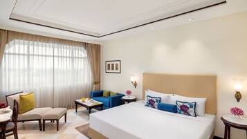 Quarto de hotel com cama grande, sofá, mesa de jantar e uma mesinha lateral.