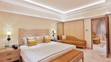 Quarto de hotel moderno com uma cama grande, um sofá e um banco.