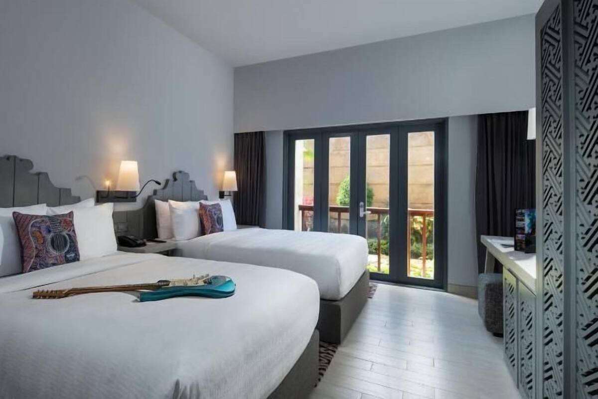 Quarto de hotel com duas camas, uma varanda e vista para o exterior.