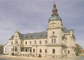 Um edifício grande e histórico com uma torre imponente e diversas janelas.