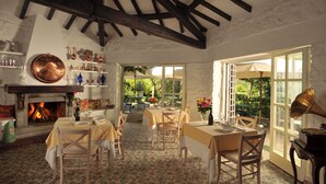 Uma sala de jantar com mesas e cadeiras, uma lareira e vista para o jardim.