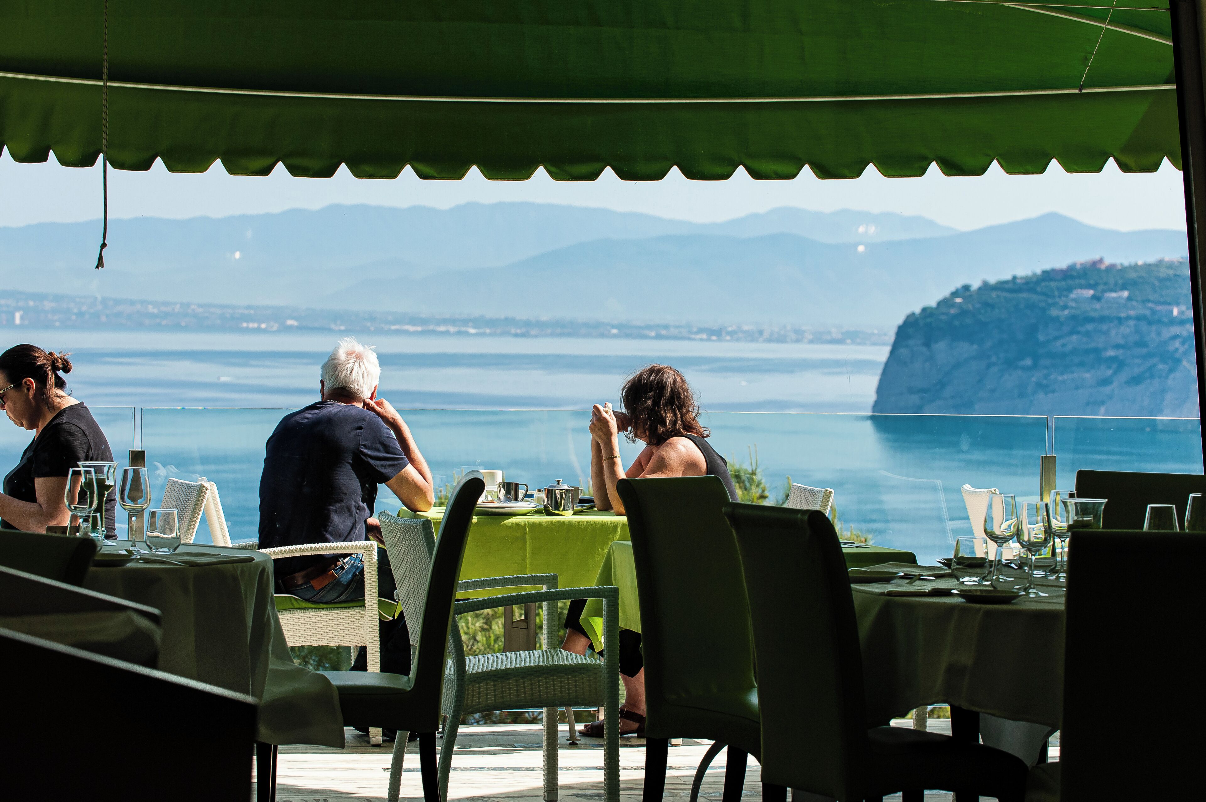 Mesa posta para refeição com vista para um lago e montanhas.