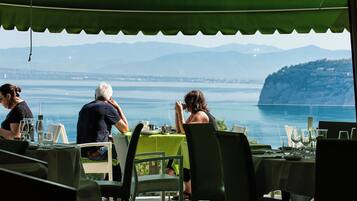 Mesa posta para refeição com vista para um lago e montanhas.