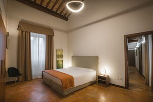 Quarto com cama grande, mesa de cabeceira, cadeira e espelho.