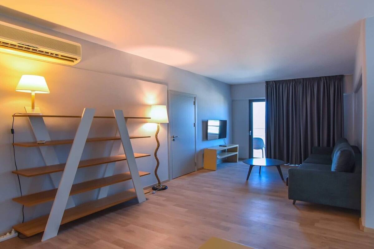 Uma sala de estar moderna com sofá, televisão e escada com luminária.