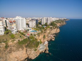 Paisagem costeira com edifícios altos, piscina e fal ésia rochosa à beira-mar.