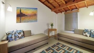 Quarto com dois sofás, uma pintura de paisagem urbana, uma pequena mesa de madeira com um vaso e uma janela com cortinas.