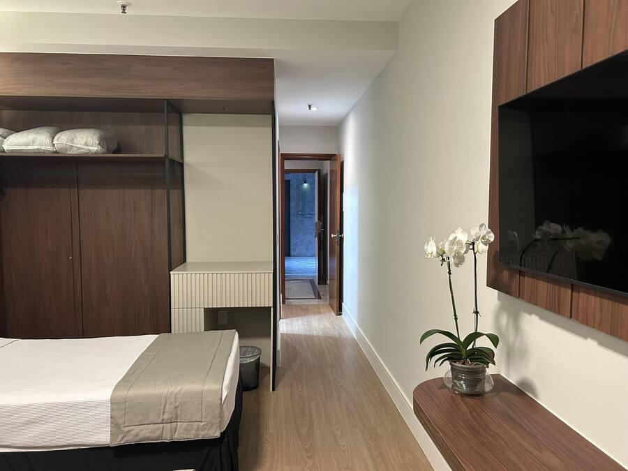 Quarto moderno com cama, guarda-roupa e um vaso de planta.