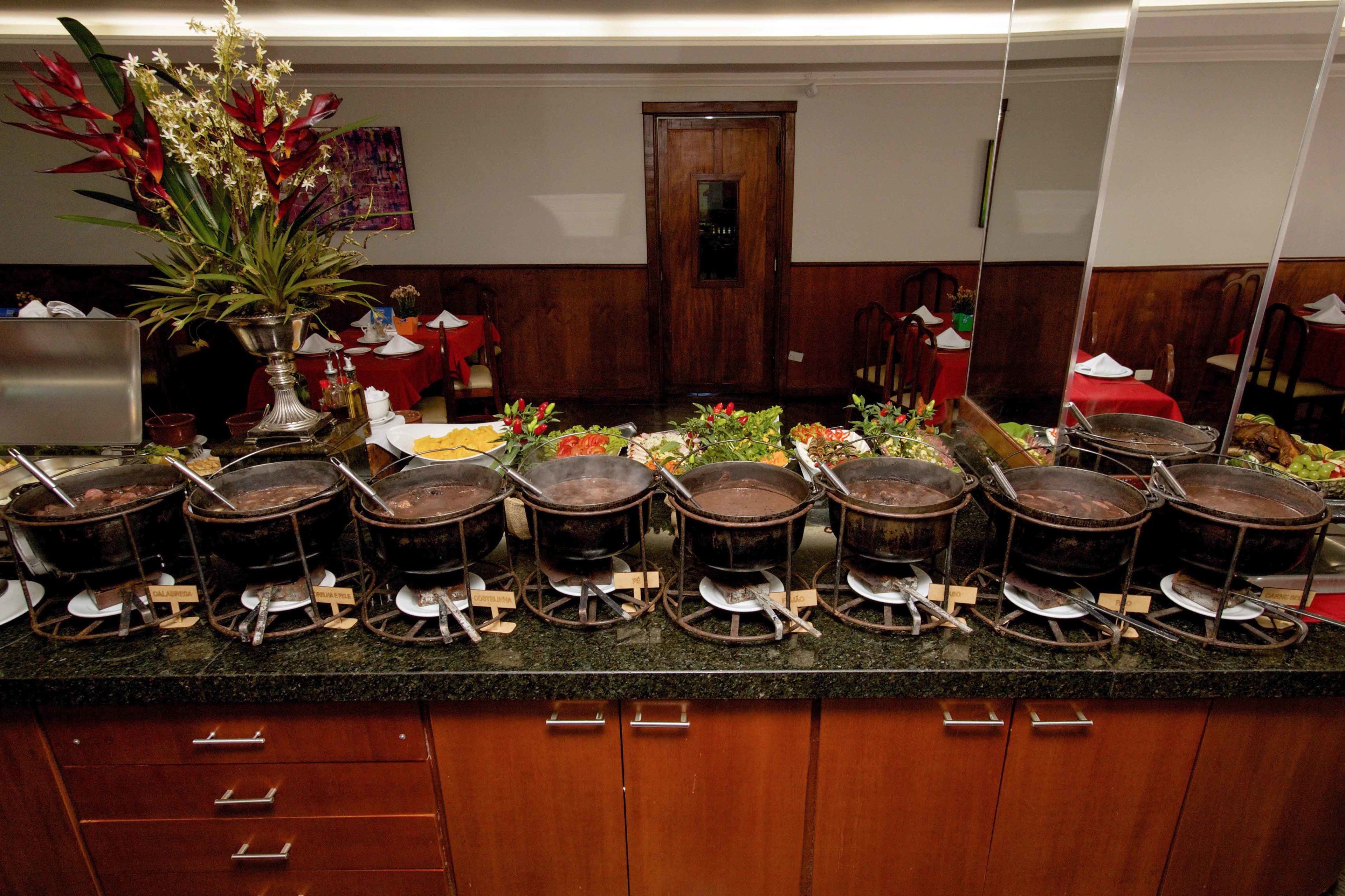 Uma mesa de buffet montada com diversas estações de serviço, um balcão de madeira e uma porta ao fundo.