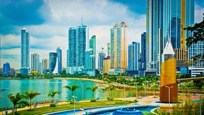 Paisagem urbana com edifícios altos, uma orla marítima e uma escultura moderna.