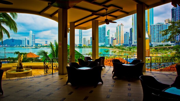 Área de estar coberta ao ar livre, com vista para o horizonte urbano e para a água.