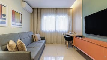 Uma sala de estar moderna com um sofá, uma televisão, um espaço de refeições e uma janela com cortinas.