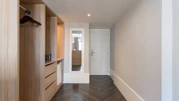 Corredor com armários de madeira, micro-ondas e porta que dá para outro quarto.