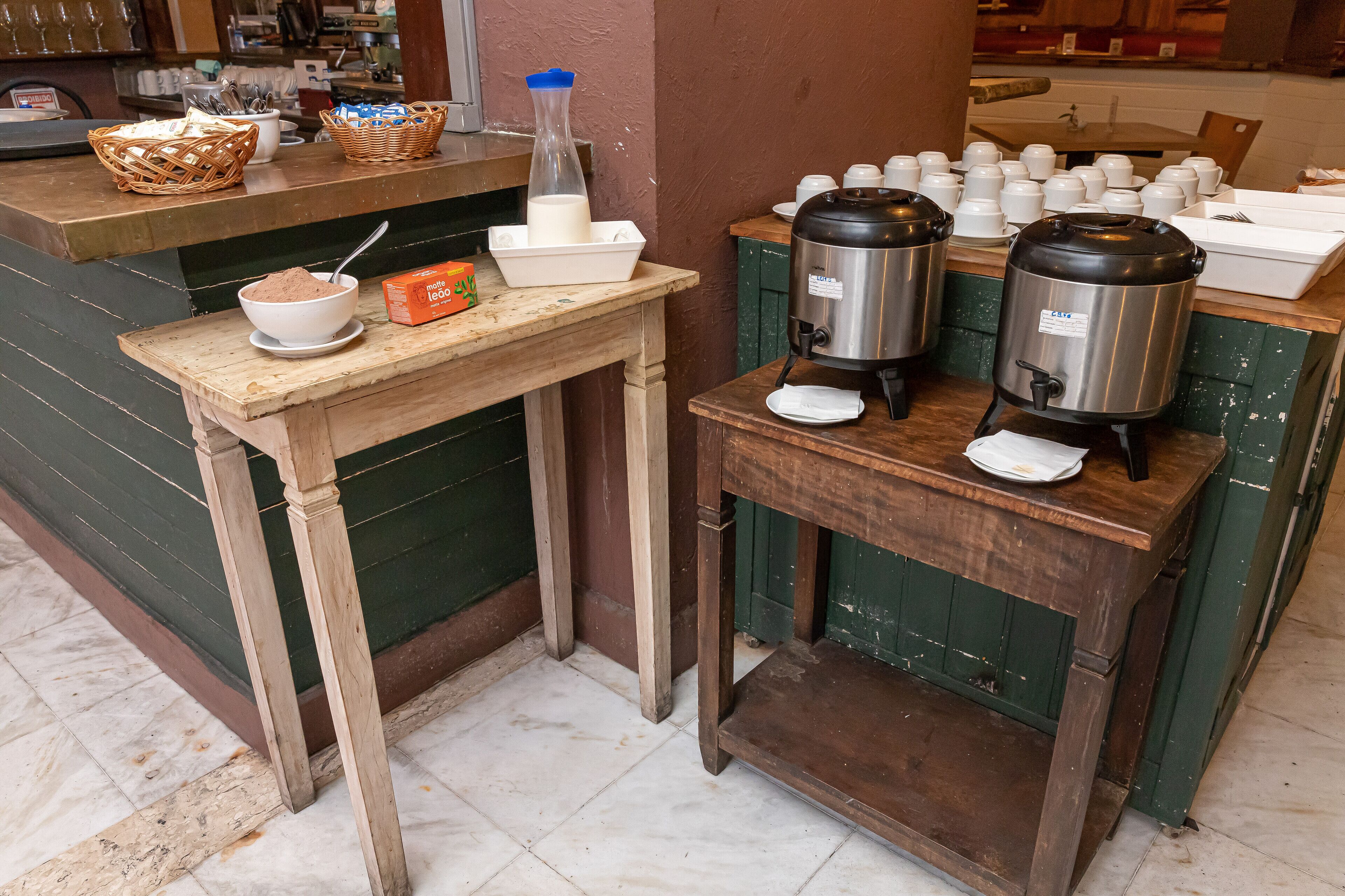Uma área de cozinha com um espaço para café, um recipiente com cacau em pó e uma caixa de chocolate em pó.