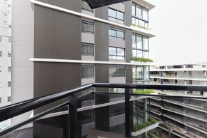 Um edifício moderno de vários andares, com varandas com plantas, janelas amplas e guarda-corpo de vidro.