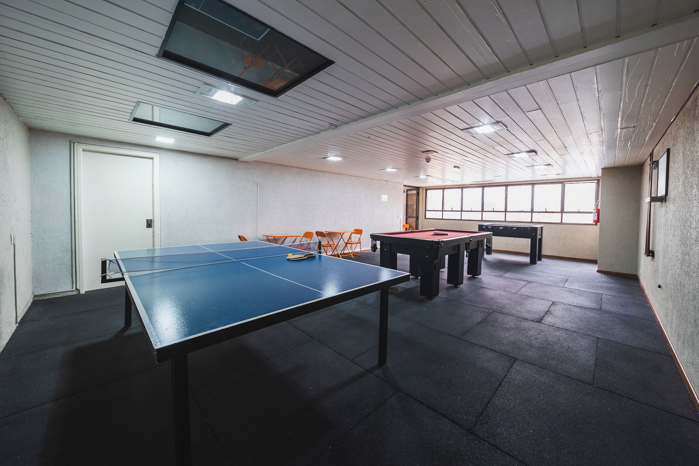 Um quarto com mesa de pingue-pongue, mesa de futebol de mesa e mesa de bilhar.