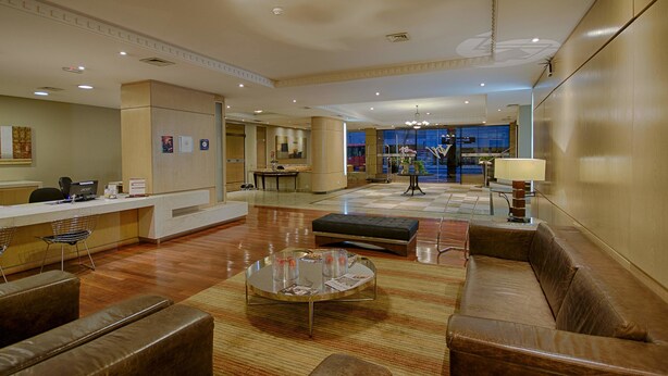 Um hall amplo com balcão de recepção, área de estar e vista para o restaurante do hotel.