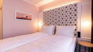 Quarto de hotel com uma cama grande, uma mesa pequena e uma parede com padrão geométrico.