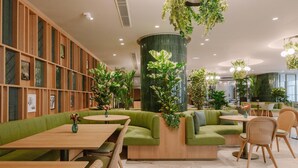 Um interior moderno com assentos verdes, painéis de madeira e plantas penduradas.