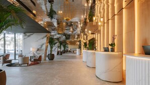 Um hall amplo com piso de mármore, assentos modernos e uma mesa de recepção.