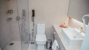 Um banheiro moderno com chuveiro envidraçado, vaso sanitário, pia e lixeira.
