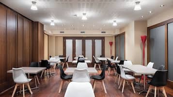 Uma sala de conferências com várias mesas e cadeiras, painéis de madeira em uma parede e um teto com iluminação embutida.