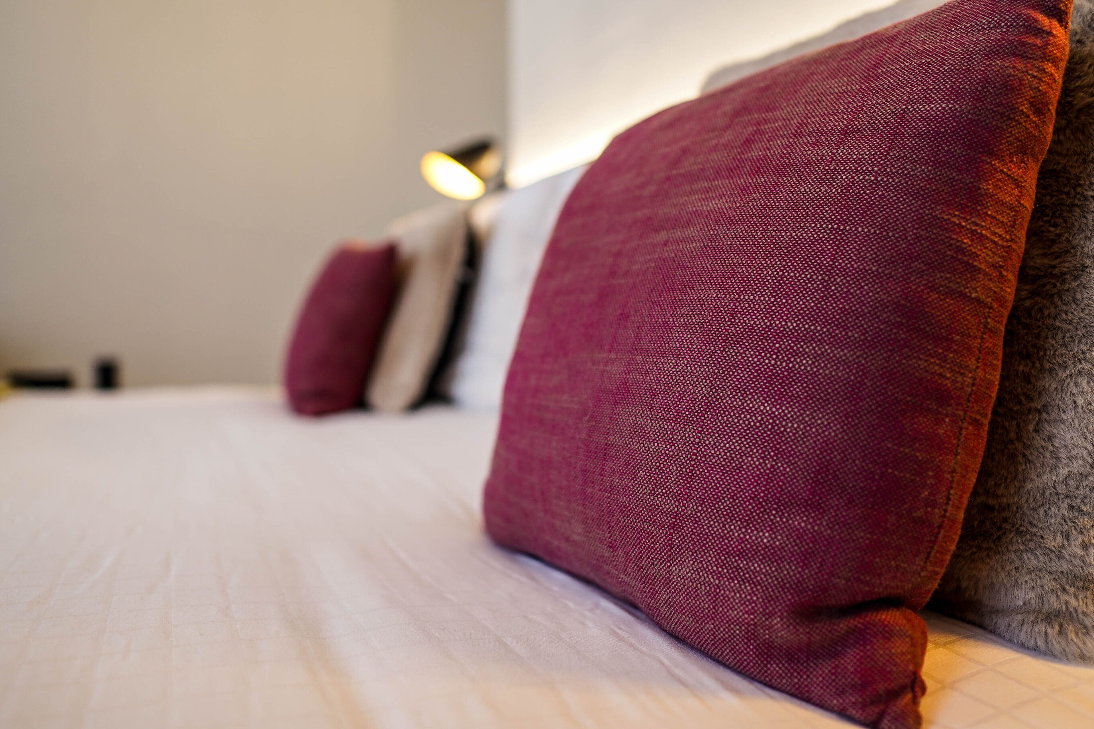 Uma cama com vários travesseiros e uma luminária de cabeceira.