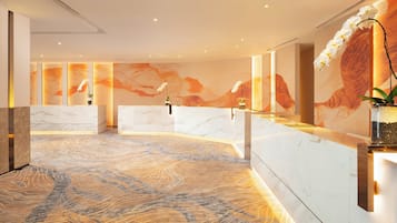 Uma área de recepção moderna com balcões de mármore, piso estampado e um grande painel decorativo.