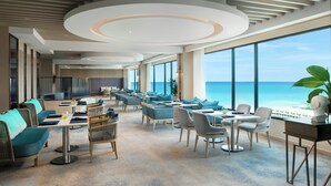 Um hall de hotel moderno com uma área de estar ampla, grandes janelas com vista para o oceano e um design de teto contemporâneo.