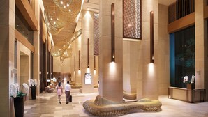 Um hall amplo com teto alto, luminárias modernas e uma área de estar central.