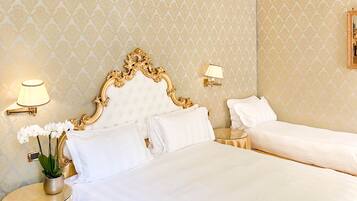 Quarto de hotel com uma cama grande, duas mesas de cabeceira, um candelabro e um espelho na parede.