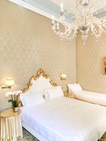 Quarto de hotel com uma cama grande, duas mesas de cabeceira, um candelabro e um espelho na parede.