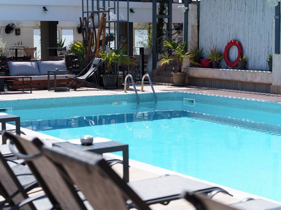 Uma área de piscina com espreguiçadeiras, um escorregador e plantas em vasos.