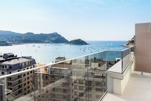 Um edifício alto com vista para a área costeira, incluindo uma praia e barcos.