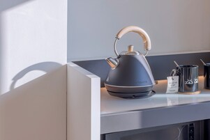 Cozinha moderna com chaleira no balcão, cafeteira e uma caneca.