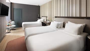 Quarto de hotel com duas camas, televisão, escrivaninha e uma cadeira.