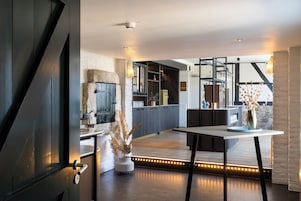 Um interior moderno com lareira de pedra, espaço de bar e escada.