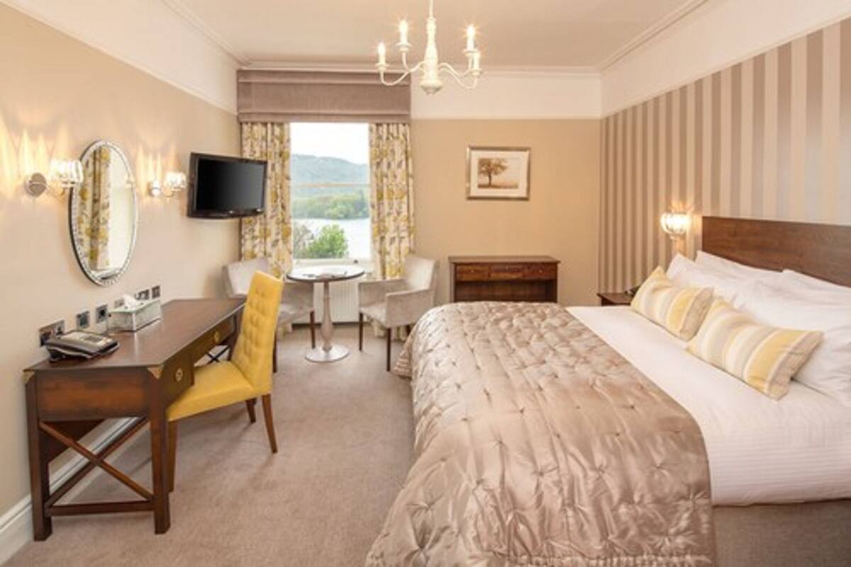 Quarto de hotel com cama, escrivaninha, cadeira, televisão e vista para o exterior.