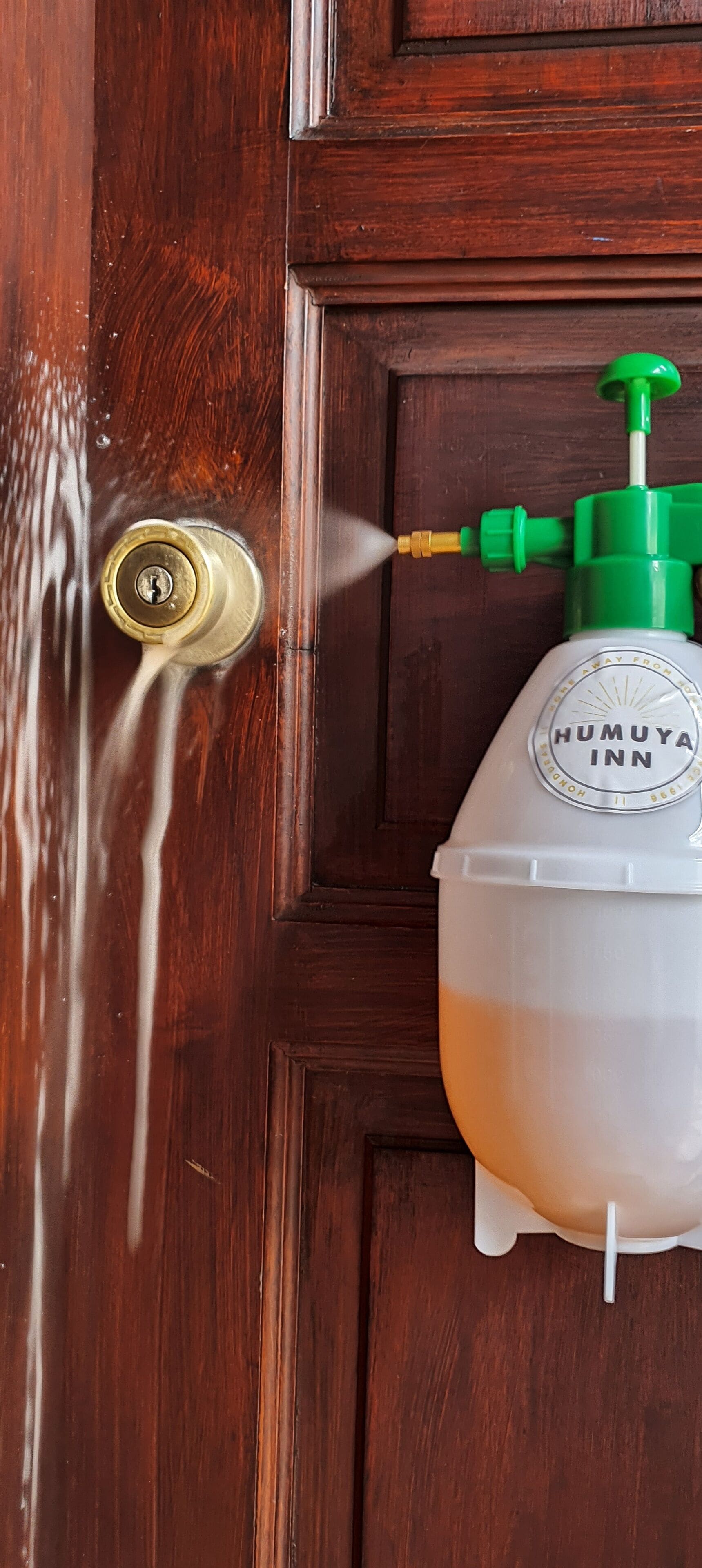 Um dispensador de água fixado numa porta de madeira, com uma etiqueta a dizer "HUMUYA INN".