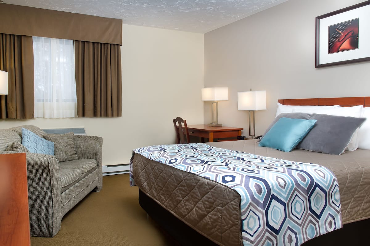 Quarto de hotel com cama, sofá, escrivaninha e cadeira.