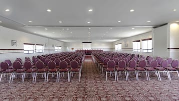 Uma sala de conferências com fileiras de cadeiras e piso coberto de carpete.