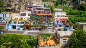 Uma vila na encosta de uma colina com edifícios coloridos, uma rua para pedestres e vista para o mar.