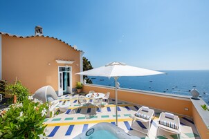 Terraço no telhado com piscina, área de estar ao ar livre e vista para o mar.